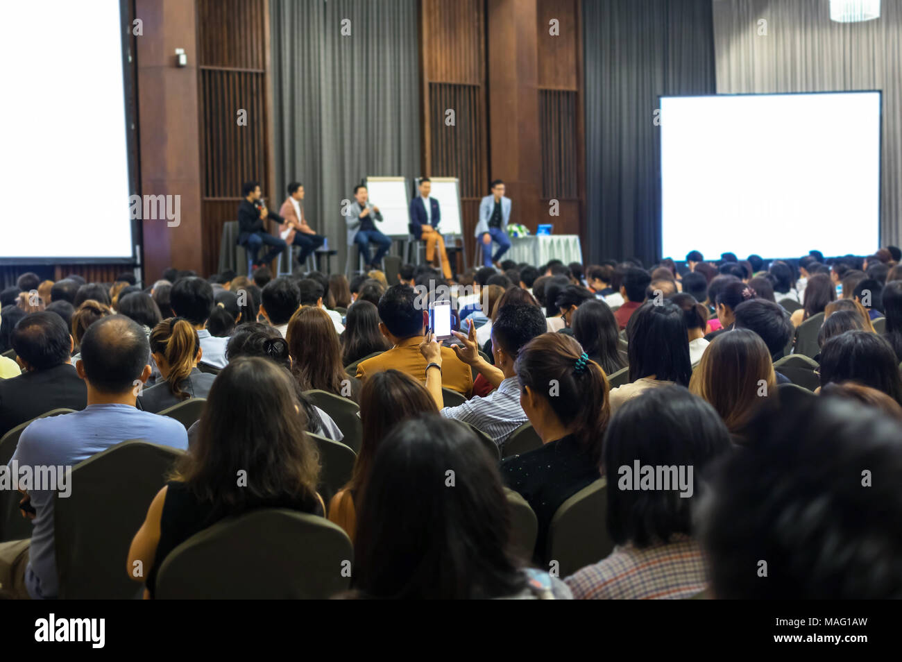 Speakers on the stage with Rear view of Audience in the conference hall ...