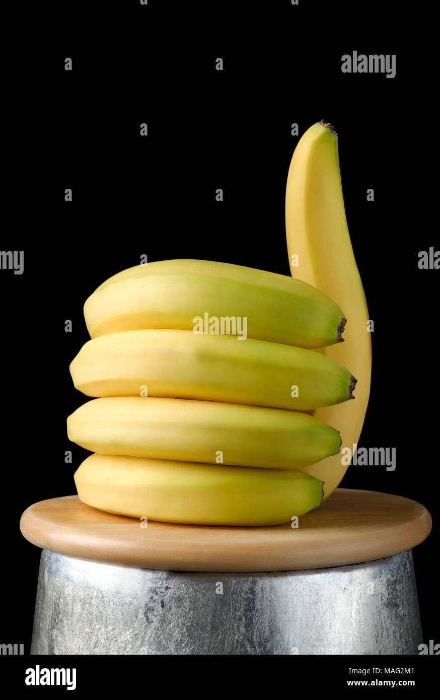 bananas lying on a wooden board in the shape of a hand with the thumb ...