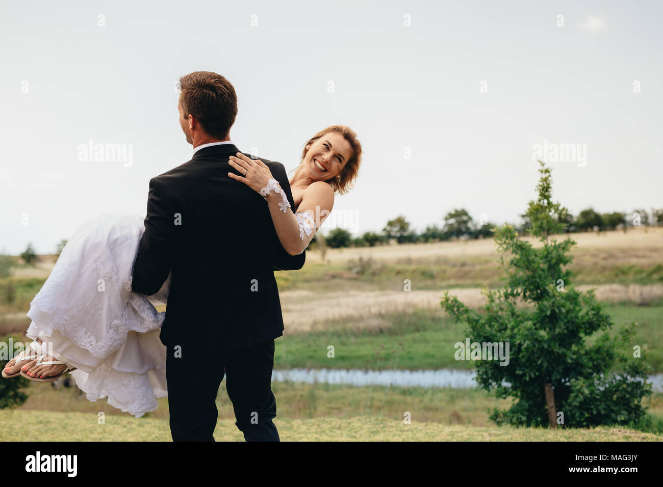 Rear view groom carrying bride hi-res stock photography and images - Alamy