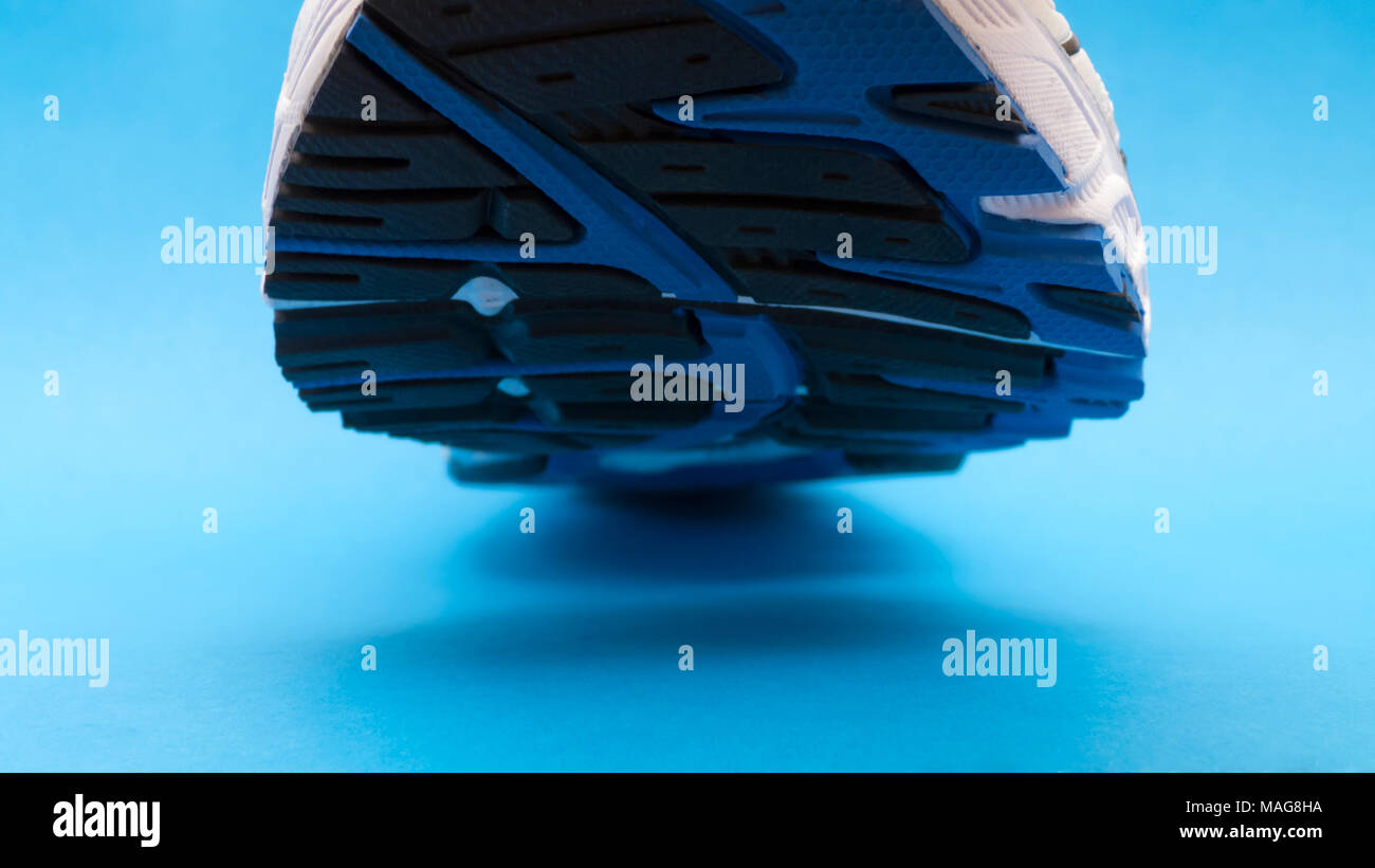 Running shoe stepping on something against blue background Stock Photo ...