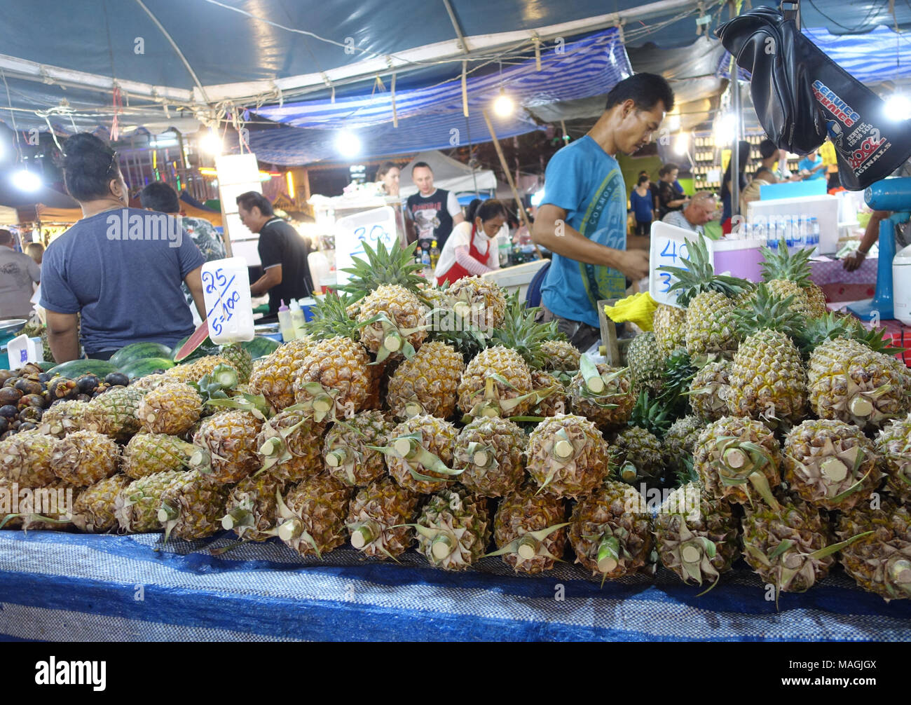 04 March 2018, Thailand, Karon Beach: A dealer sells pineapples and ...