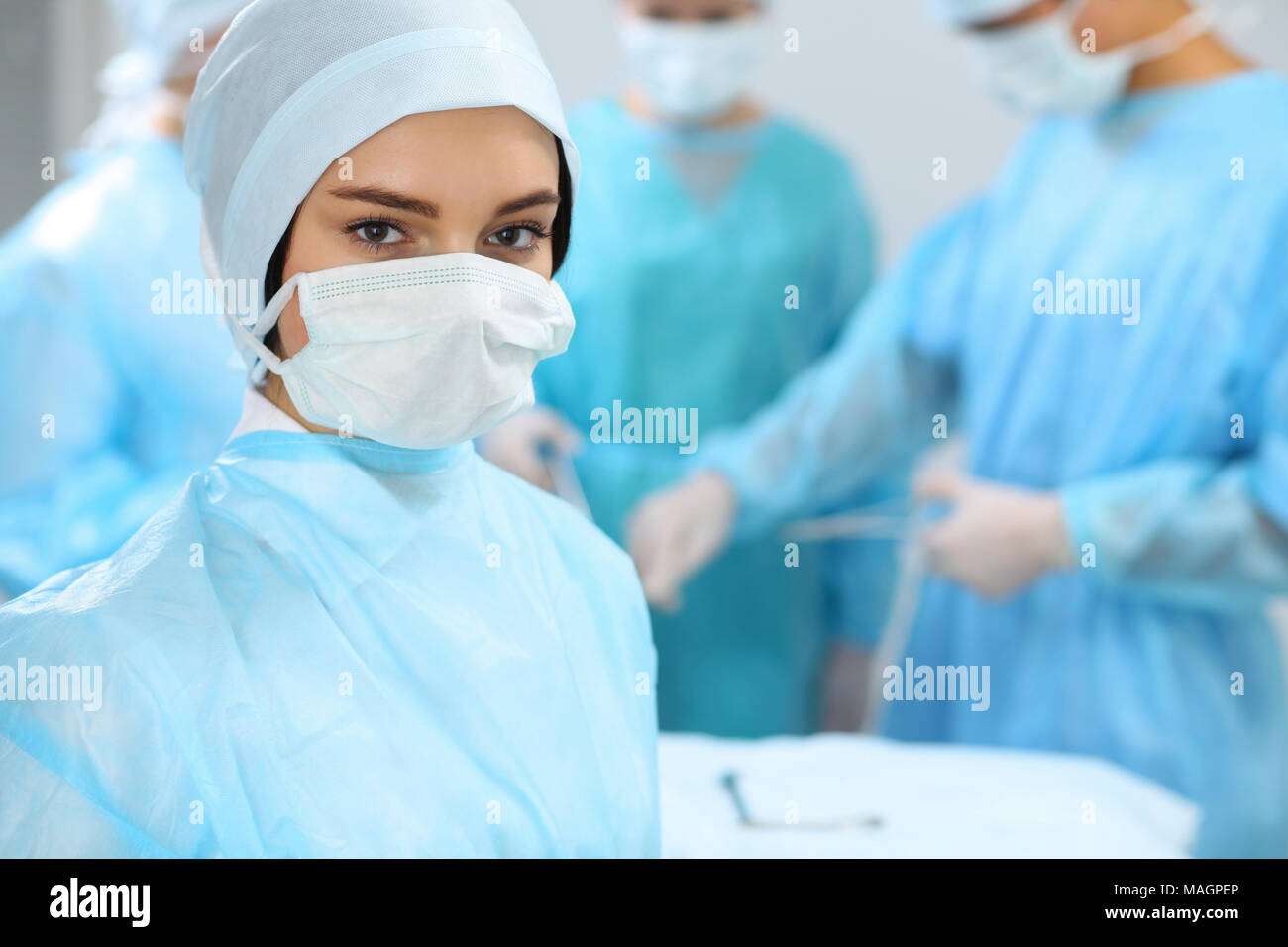 Medical team in masks performing operation. Focus on female doctor or ...