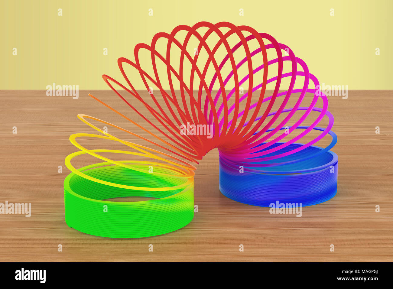 Rainbow colored plastic, slinky toy on the wooden table. 3D rendering ...