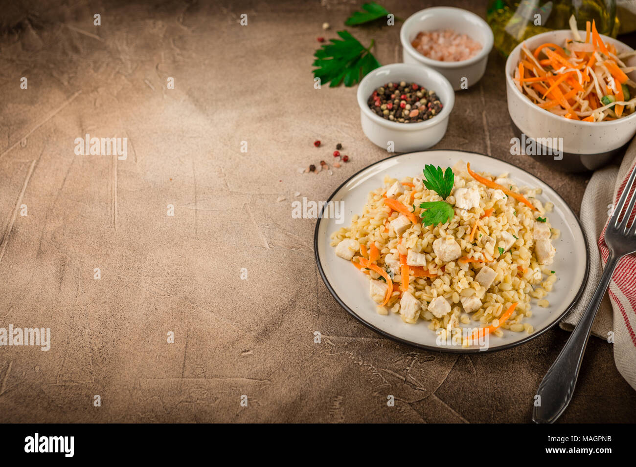 Bulgur Pilaf with chicken in a plate and a bowl of coleslaw on a brown ...
