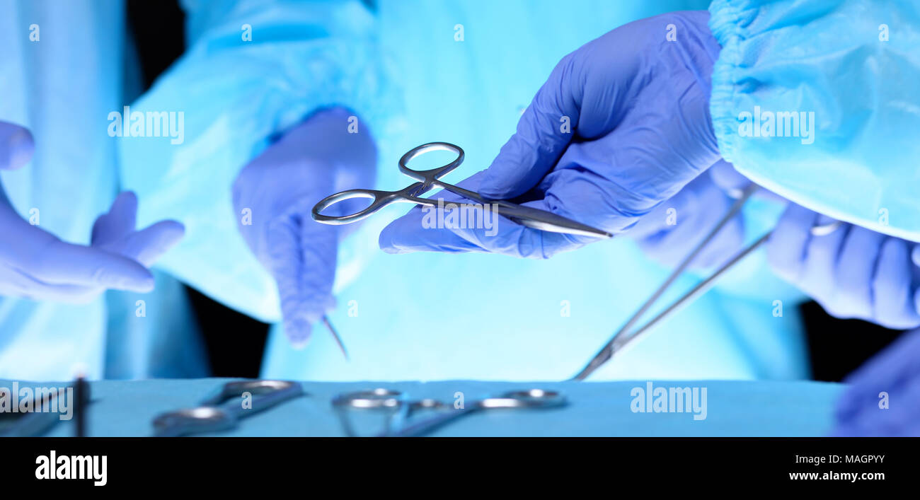 Surgeons hands holding surgical scissors and passing surgical equipment ...