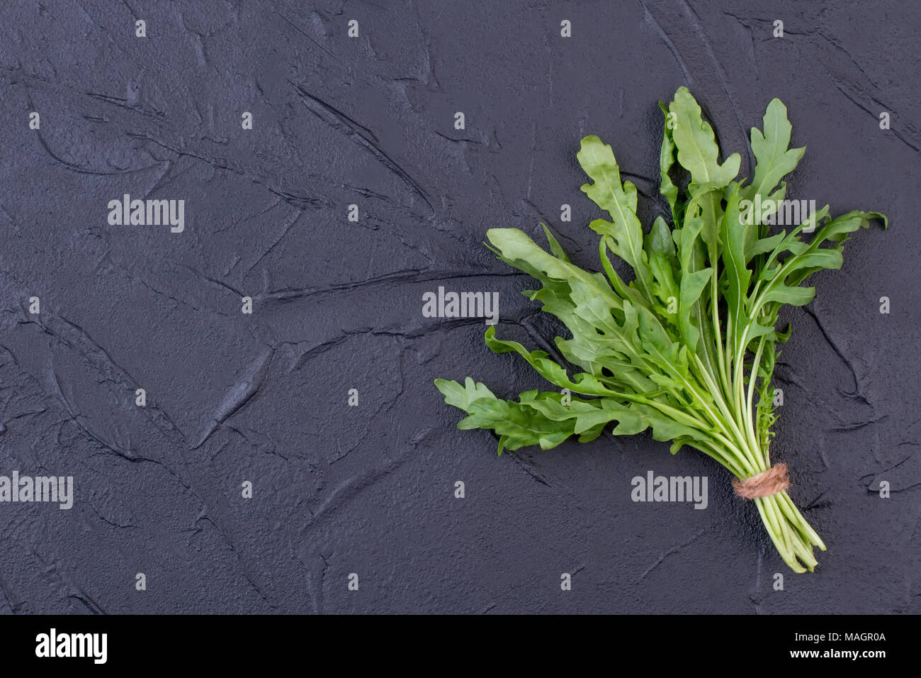 Arugula on slate board, copy space. Bunch of fresh rucola on natural ...