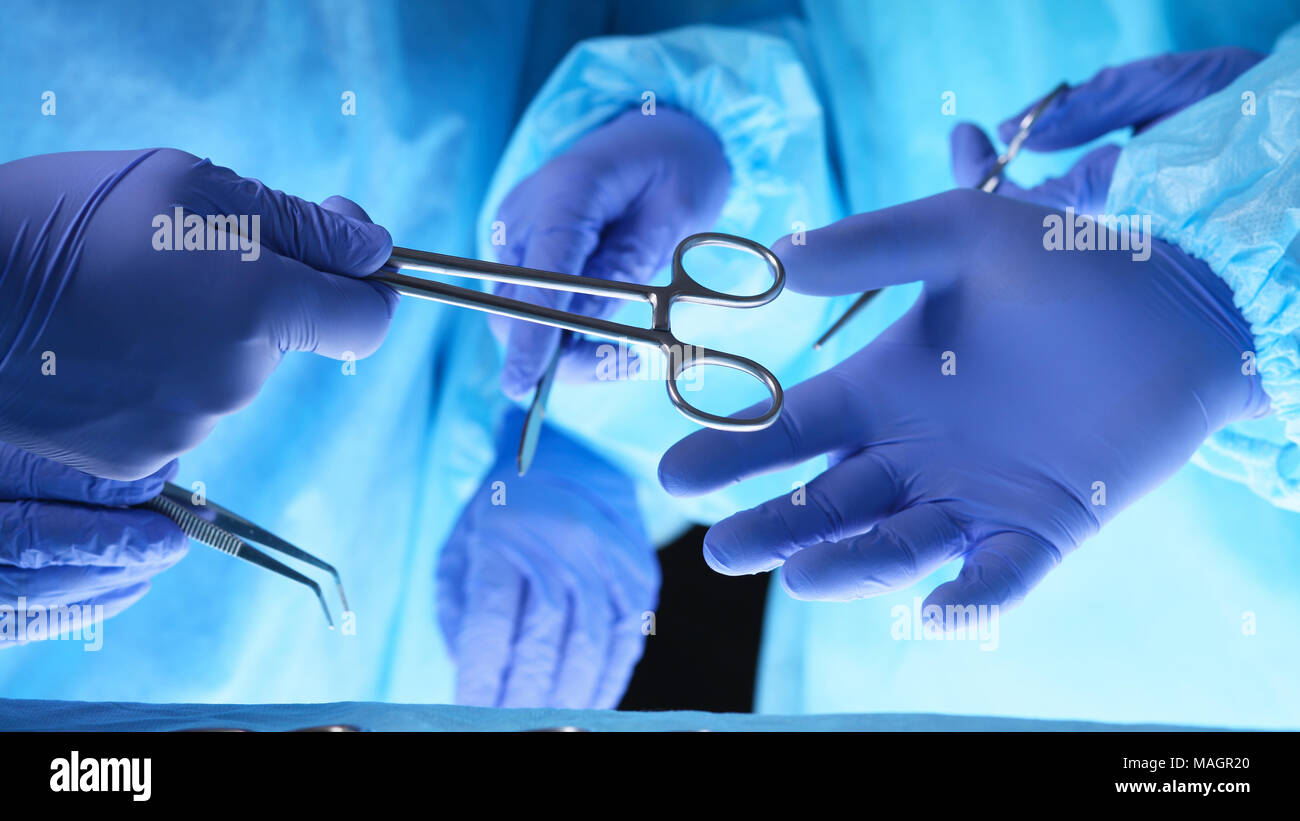 Surgeons hands holding surgical scissors and passing surgical equipment ...