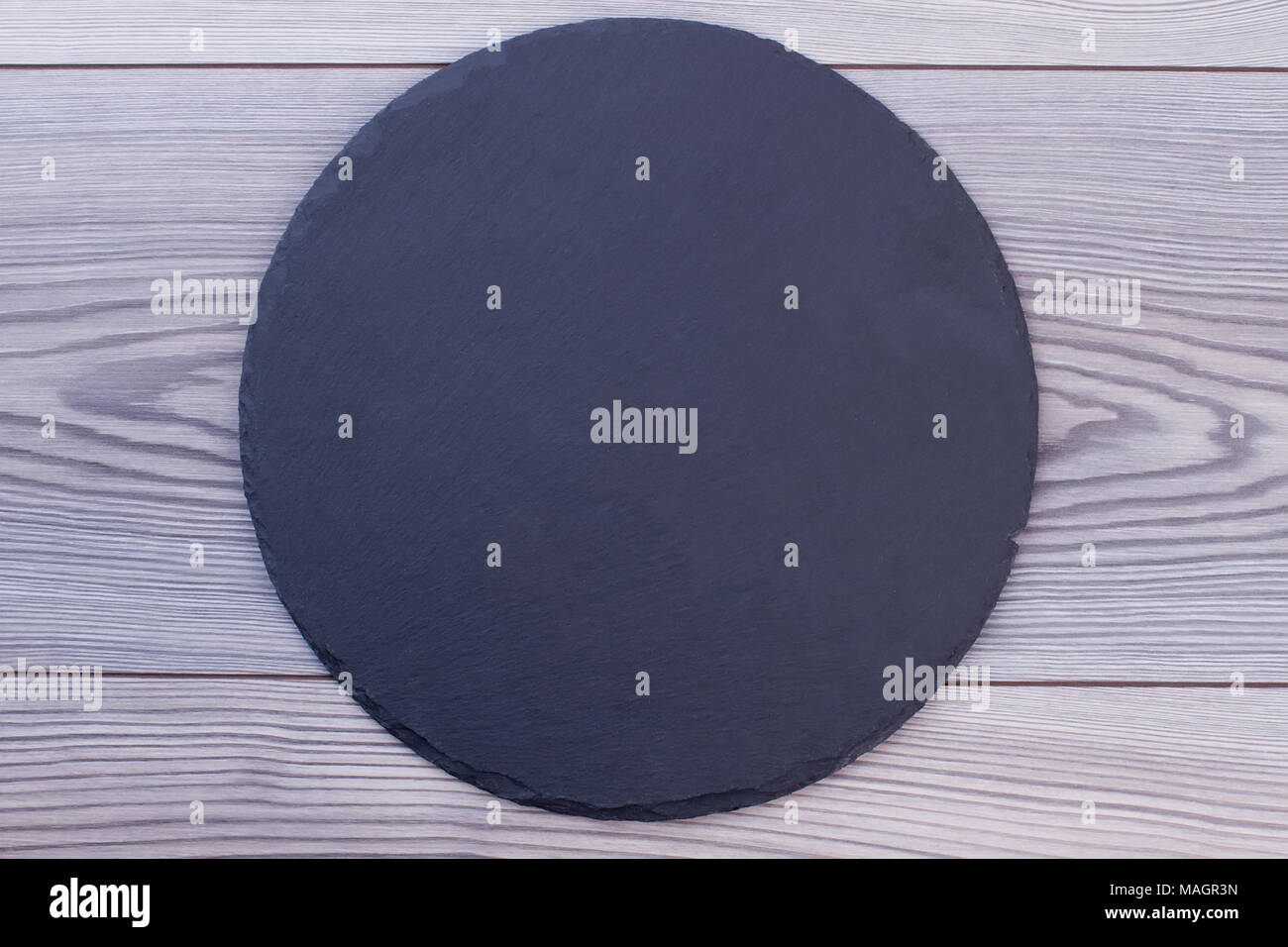 Round slate board, top view. Black slate tray on wooden textured ...