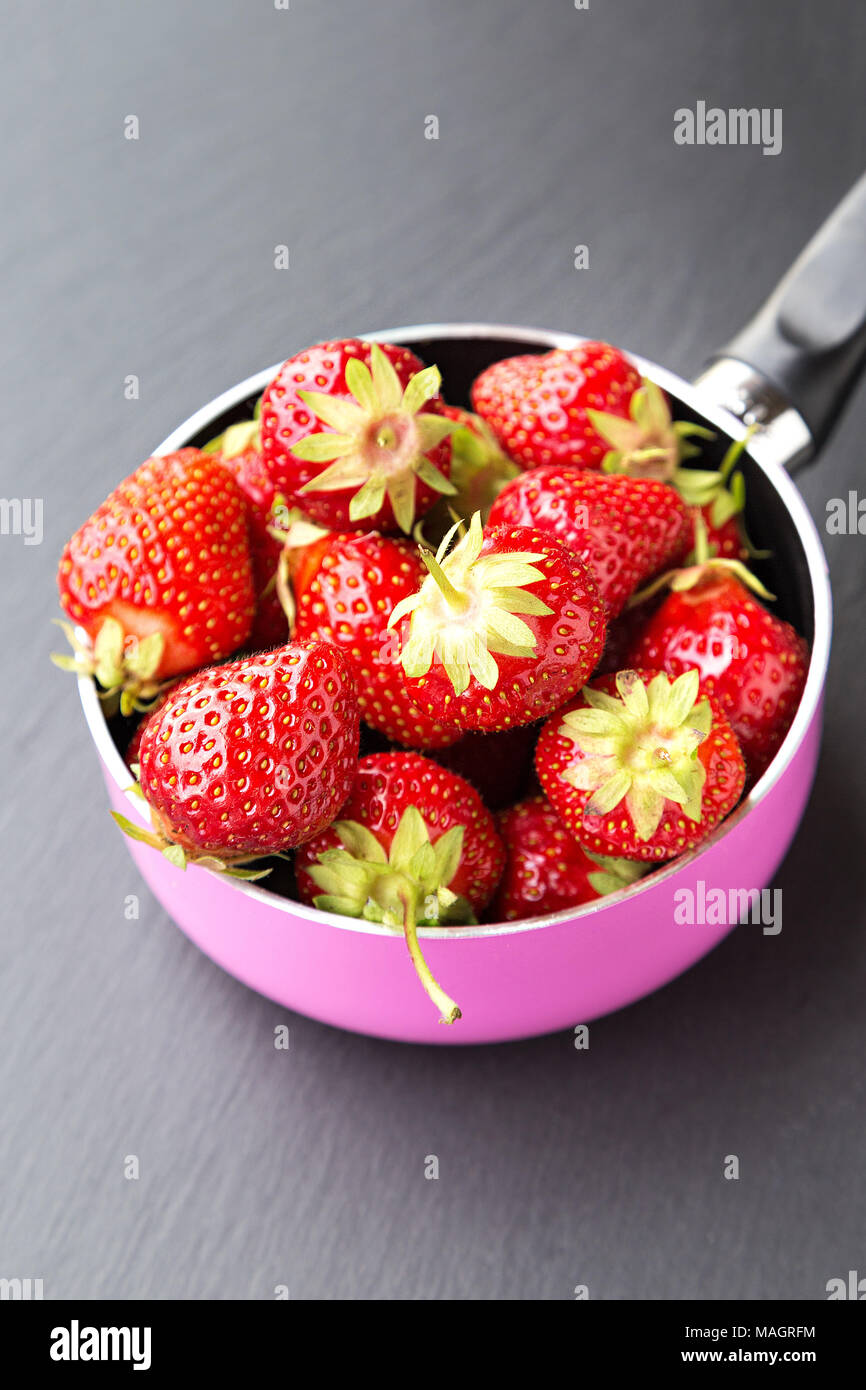 Ripe juicy strawberries in a pink dipper on slate surface Stock Photo ...