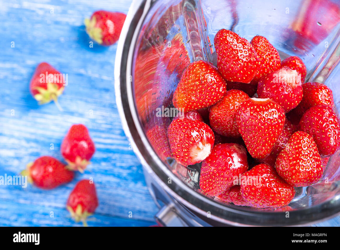 peeled ripe strawberries in a blender on a blue wooden table Stock ...