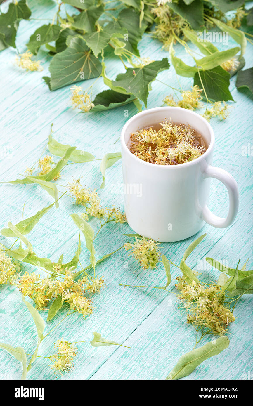 Lime brewed tea in a cup on a wooden table. on a table scattered linden ...