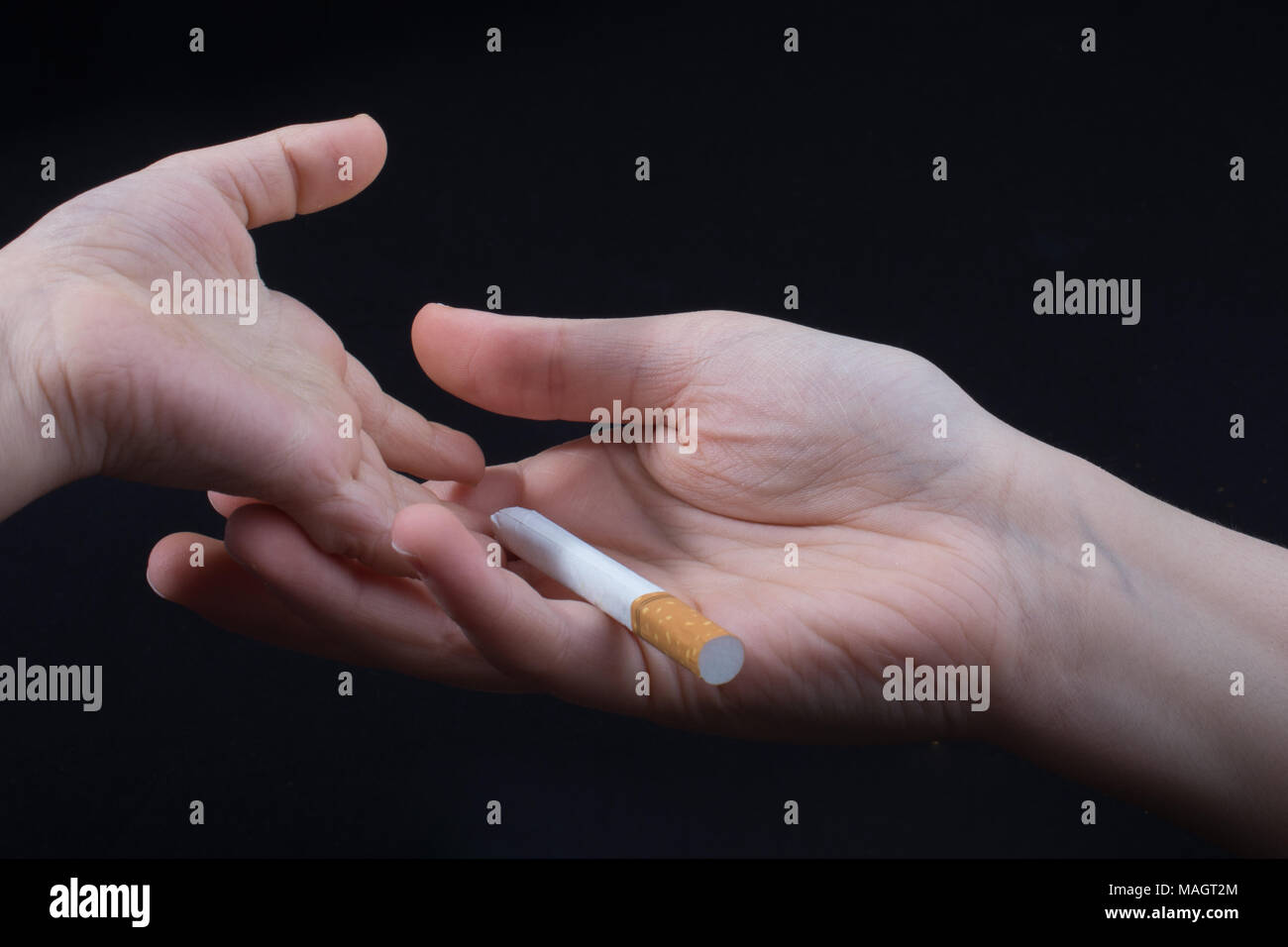 Hand is giving out cigarette on a black background Stock Photo - Alamy