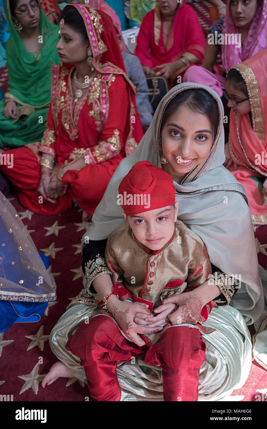 Guests including a mother & young son attending a Sikh wedding ceremony ...