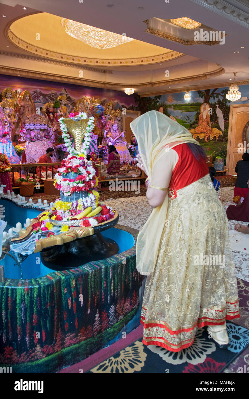 A Hindu worshiper praying & meditating in front of a statue of the god ...