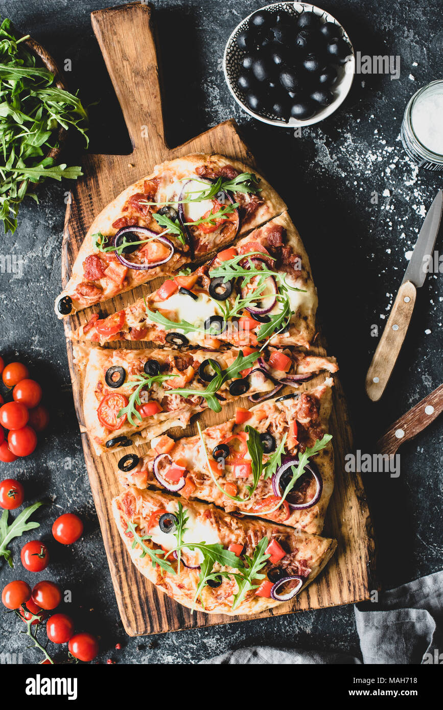 Flatbread pizza garnished with fresh arugula on wooden pizza board, top ...