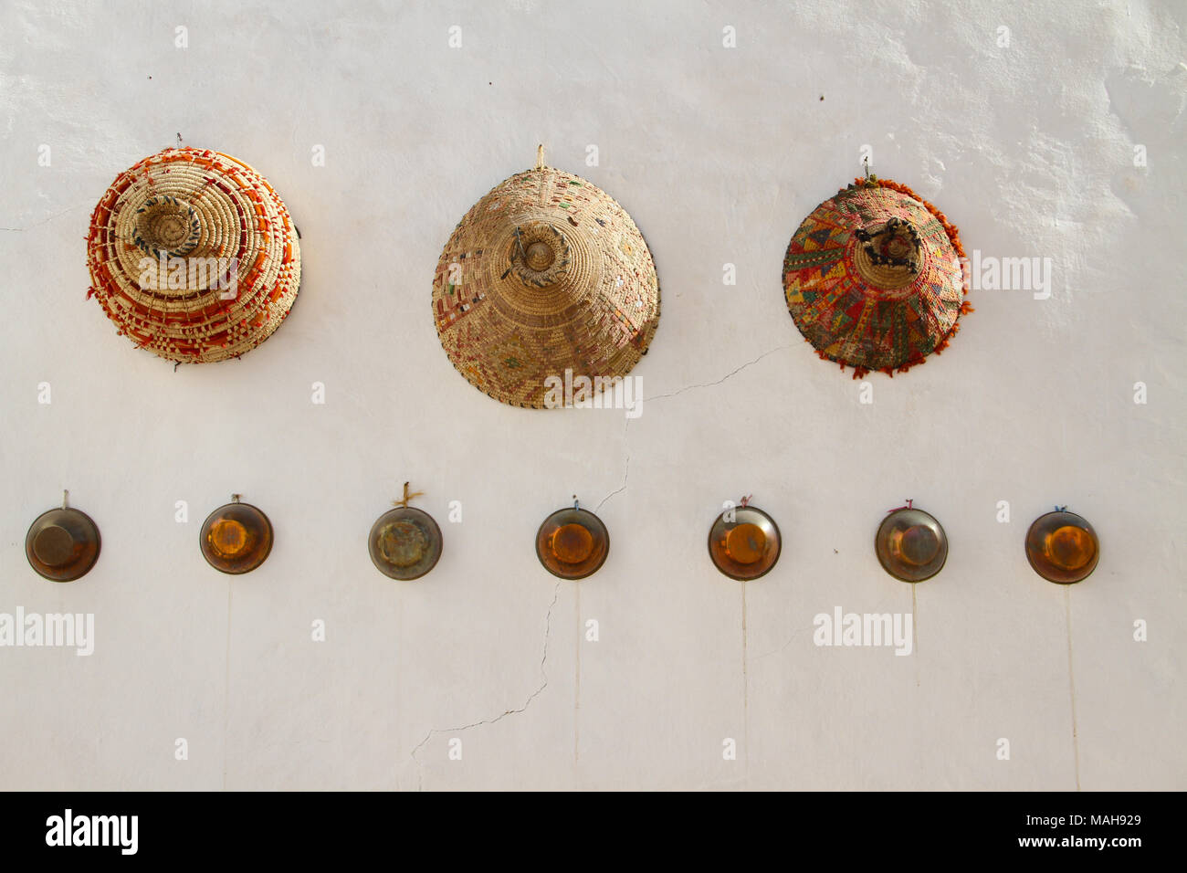 Hand woven straw hats hanging against whitewashed walls in ancient city ...