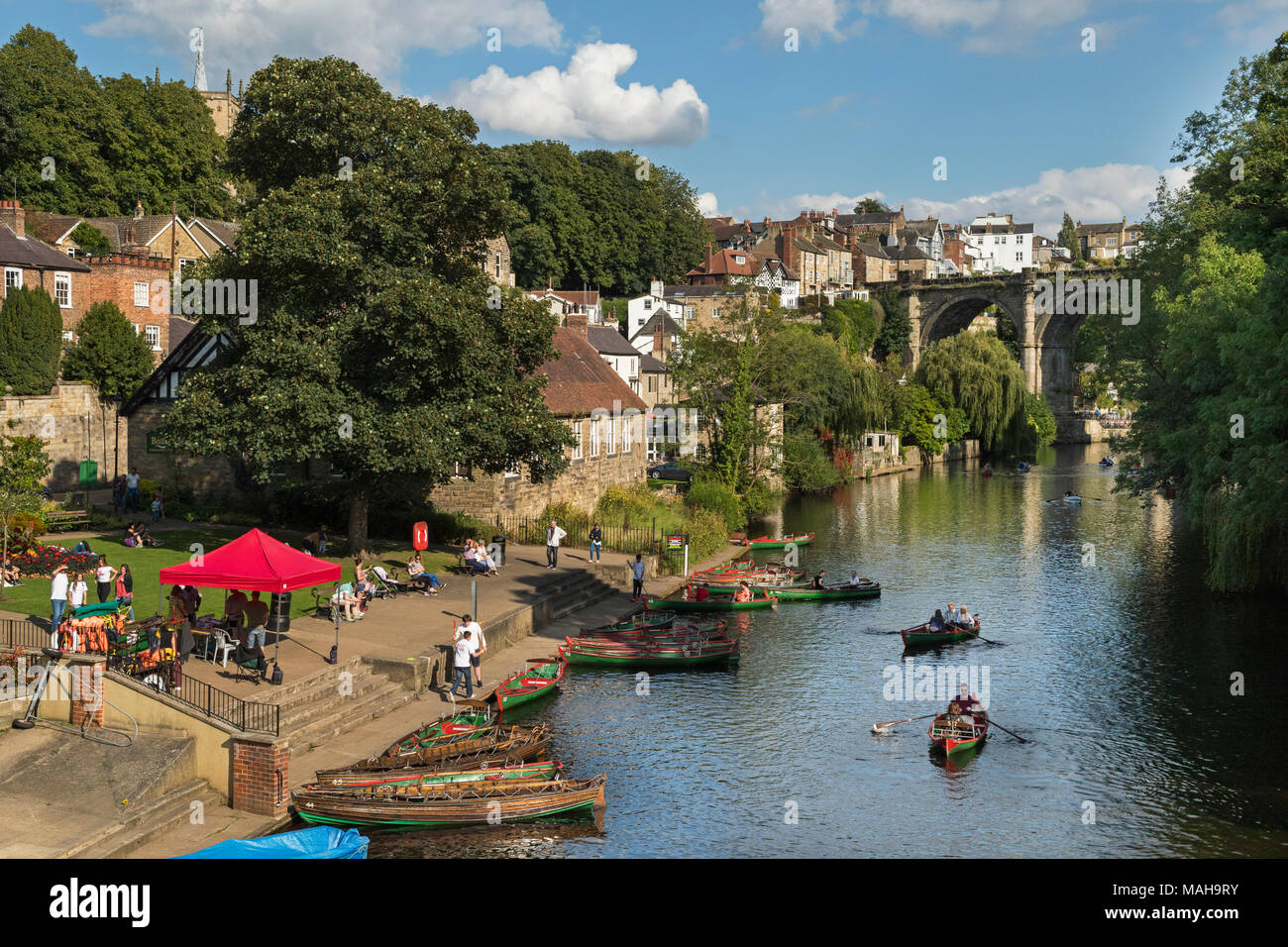 People relaxing by riverside & boating in rowing boats on River Nidd ...