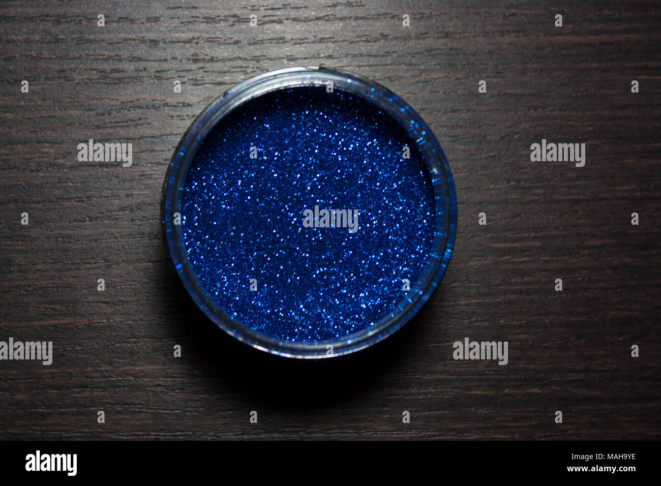 Cobalt blue glitter powder isolated on dark wooden background from a ...