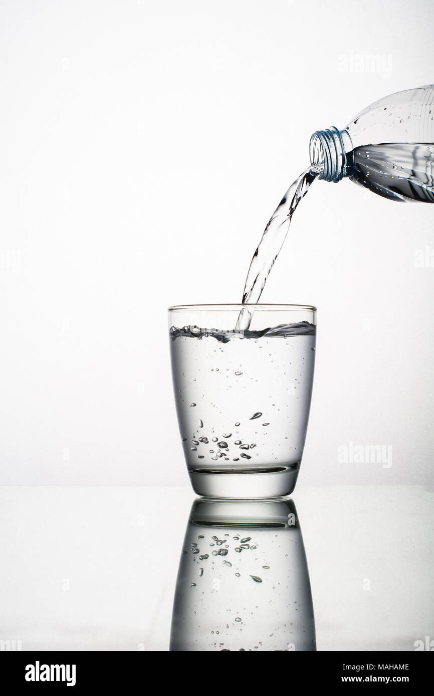 Close up of pouring water splashing from glass isolated on white ...