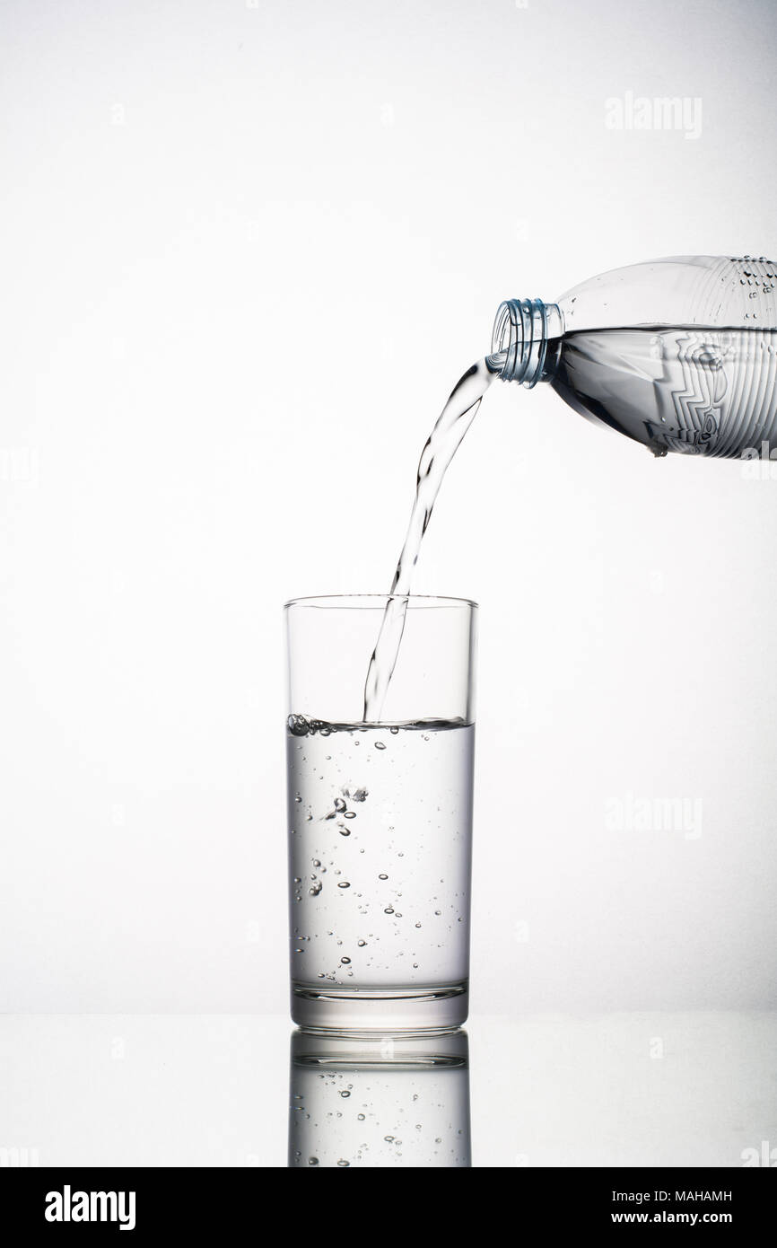 Close up of pouring water splashing from glass isolated on white ...