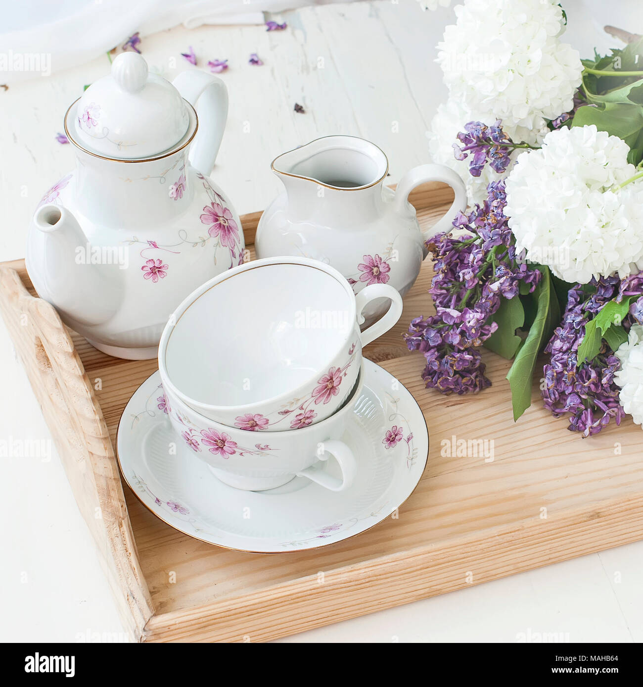 White tea set, a bouquet of lilac in a vase and a sprig of lilac in a ...