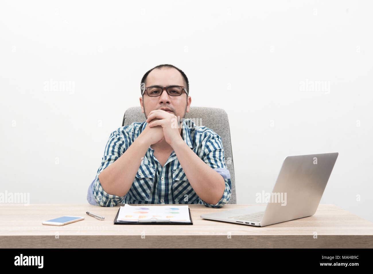 Portrait of businessman sitting behind table isolated on white ...