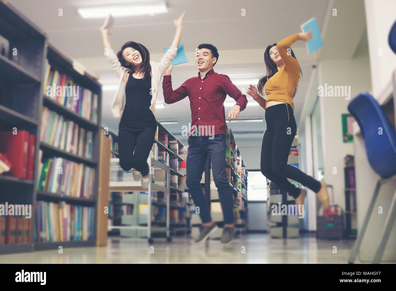Group of student jumping in the library seem so happy Stock Photo - Alamy