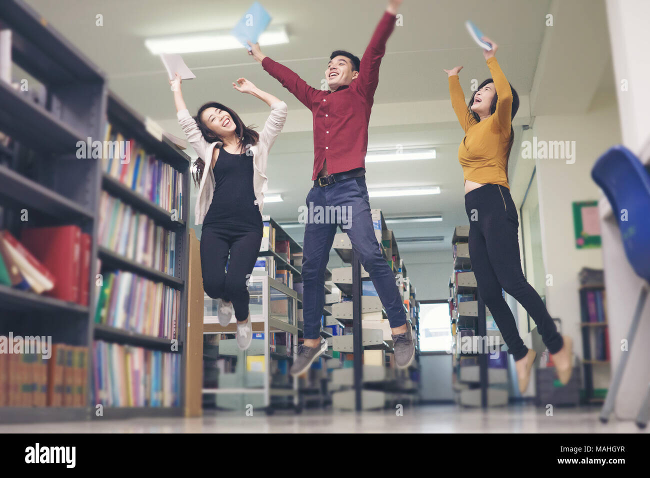 Group of student jumping in the library seem so happy Stock Photo - Alamy
