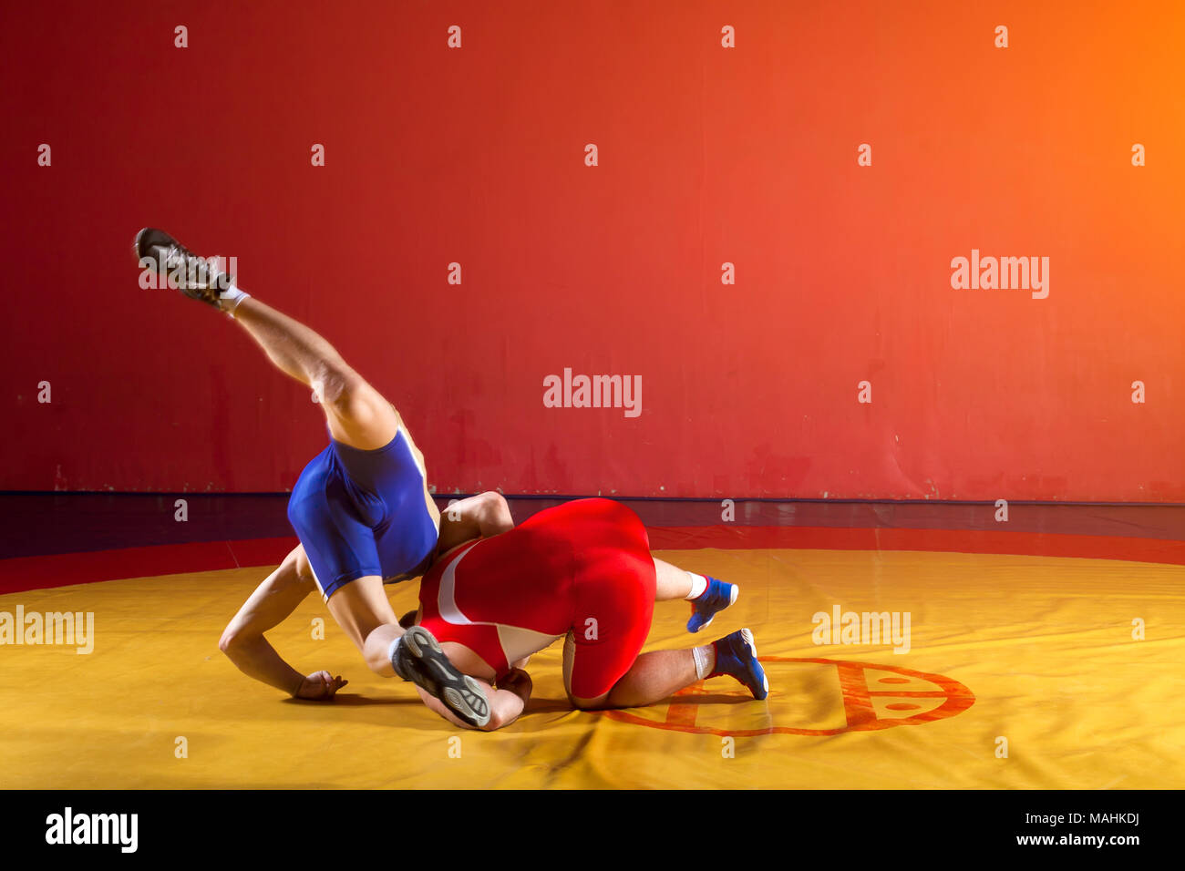 Two greco-roman wrestlers in red and blue uniform making a suplex ...