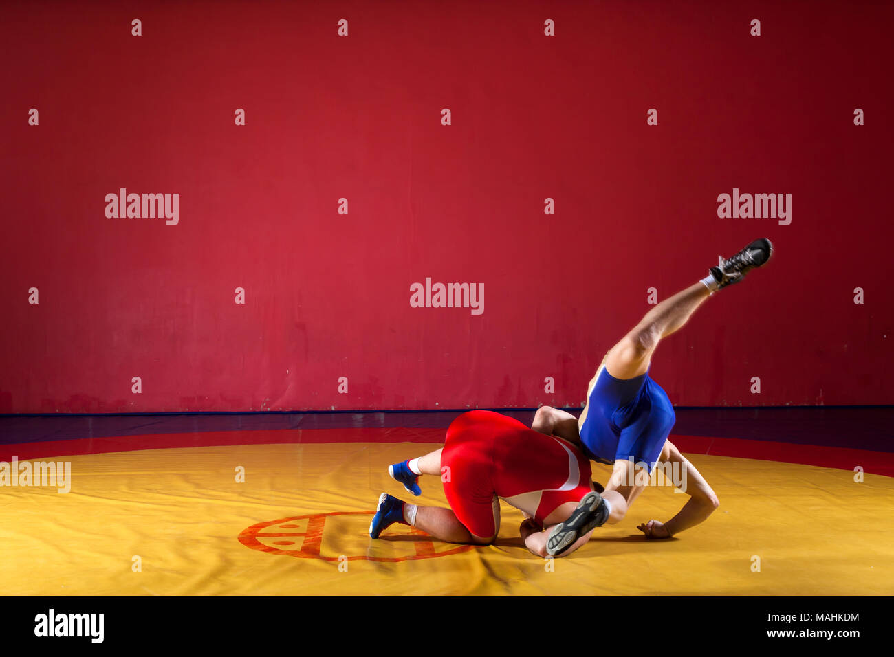 Two greco-roman wrestlers in red and blue uniform making a suplex ...