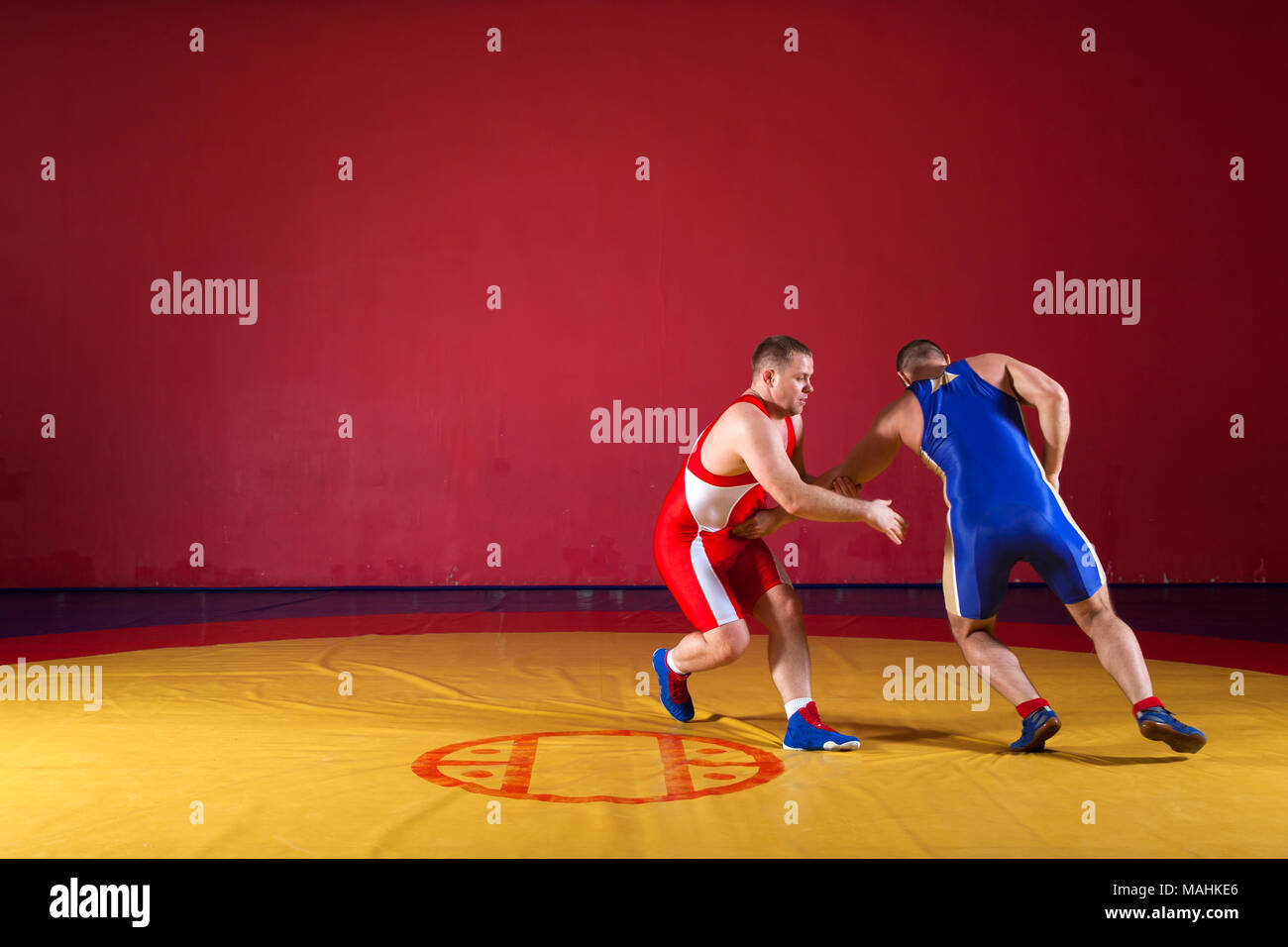 Two greco-roman wrestlers in red and blue uniform making a suplex ...
