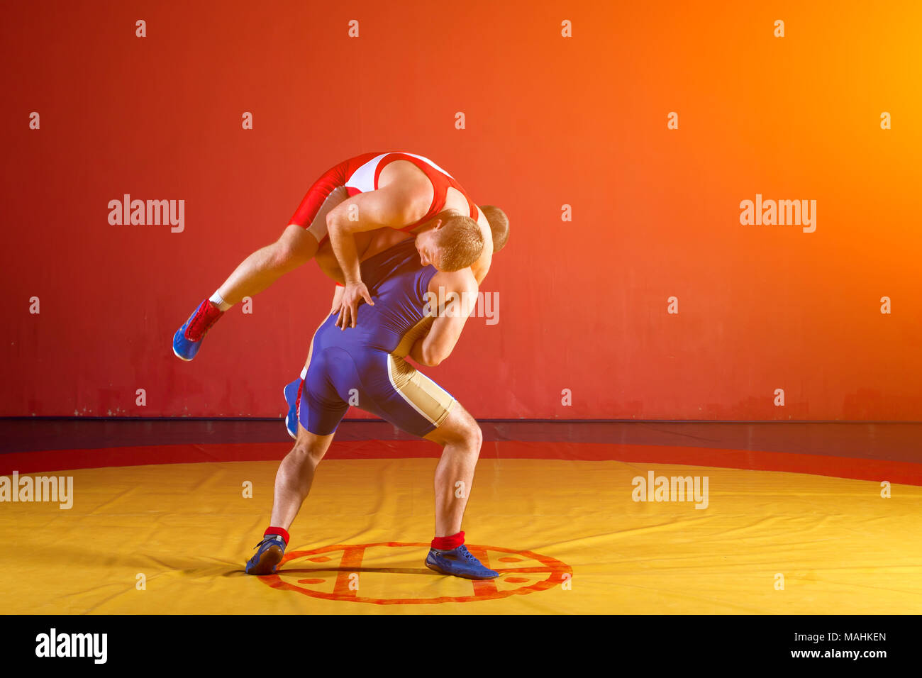 Two greco-roman wrestlers in red and blue uniform making a suplex ...