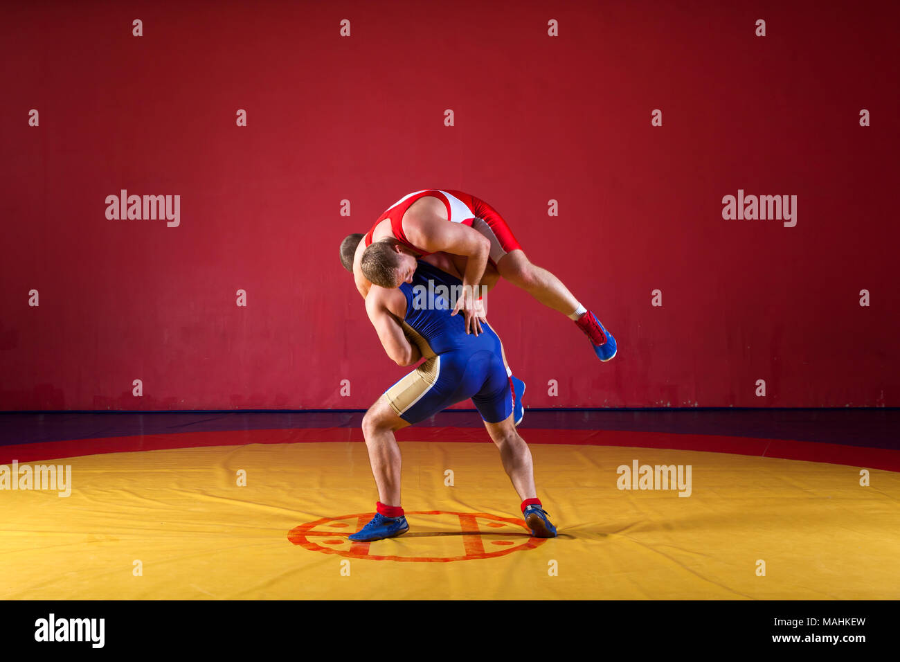 Two greco-roman wrestlers in red and blue uniform making a suplex ...