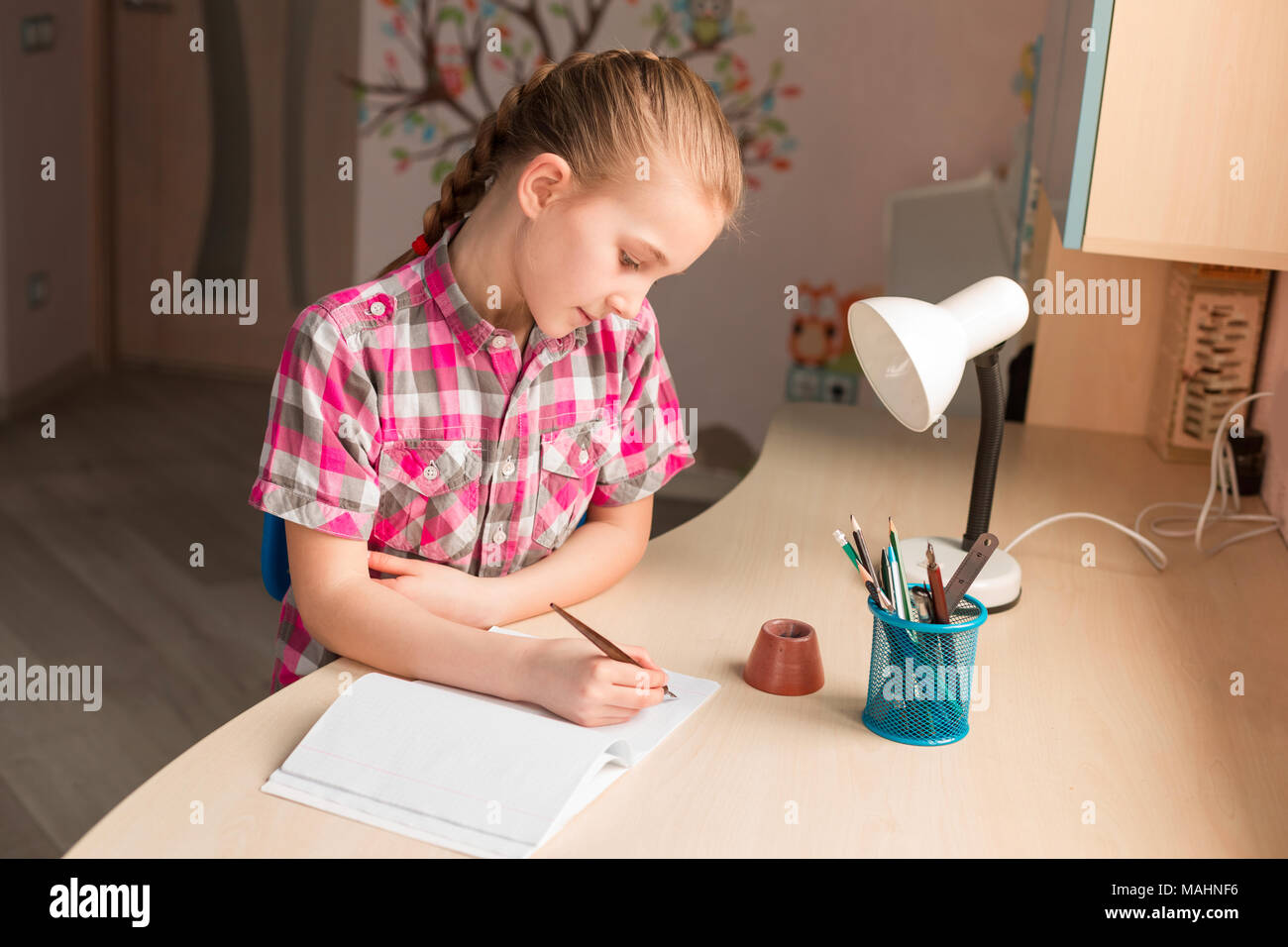 Cute little girl writing her homework at the table, left-handed Stock ...