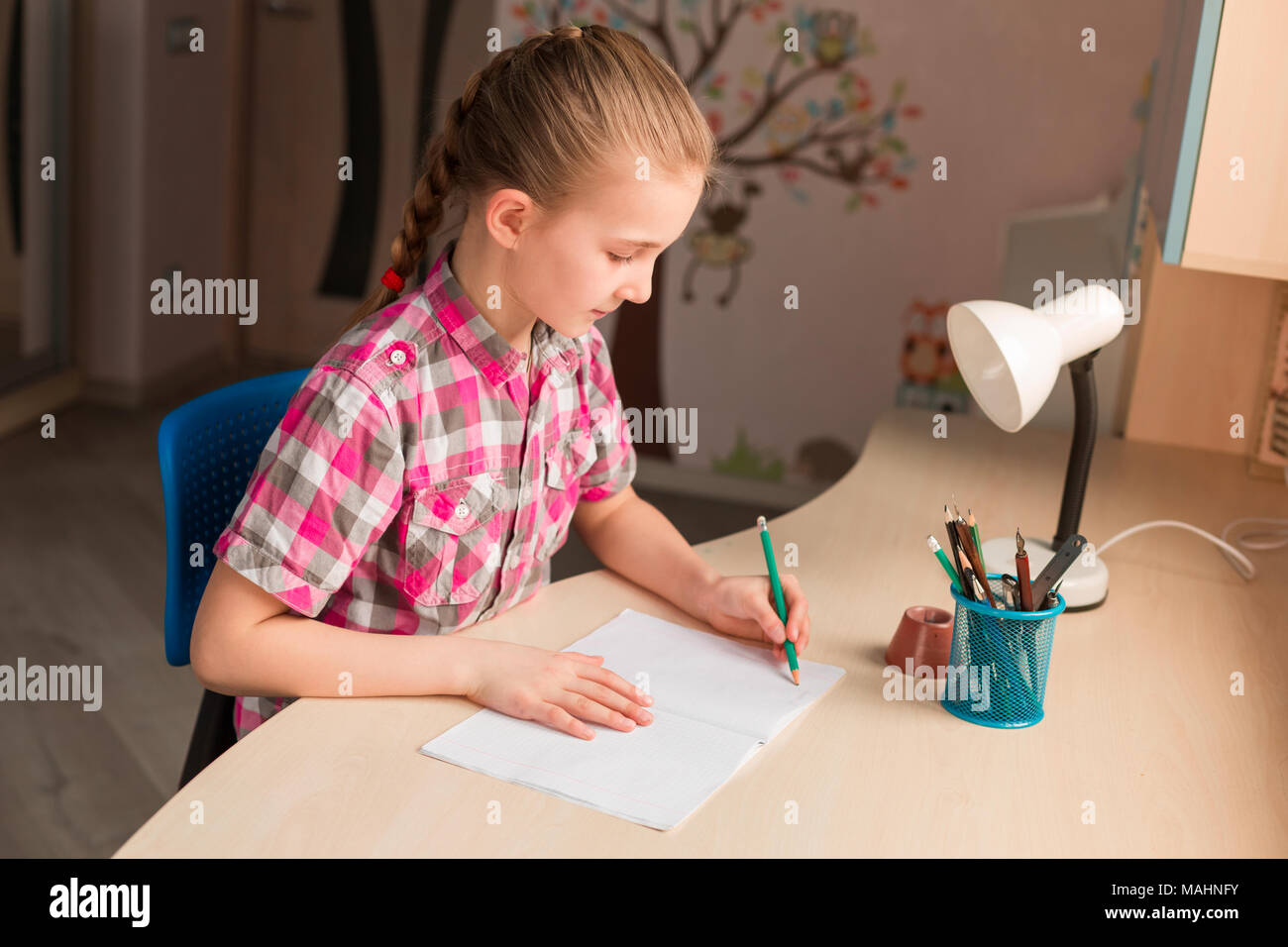 Cute little girl writing her homework at the table, left-handed Stock ...