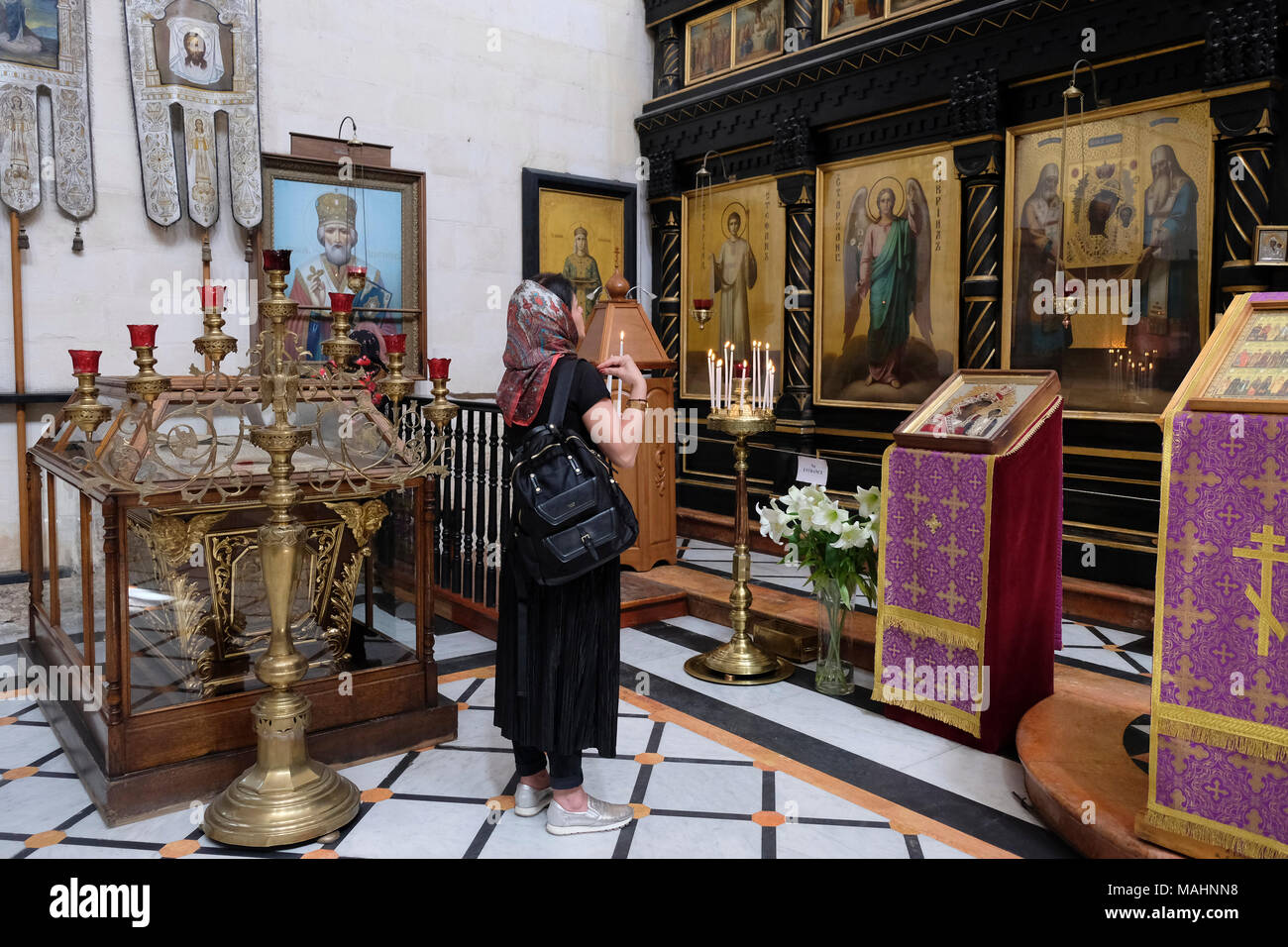 A Russian Orthodox pilgrim prays next to the iconostasis with religious ...