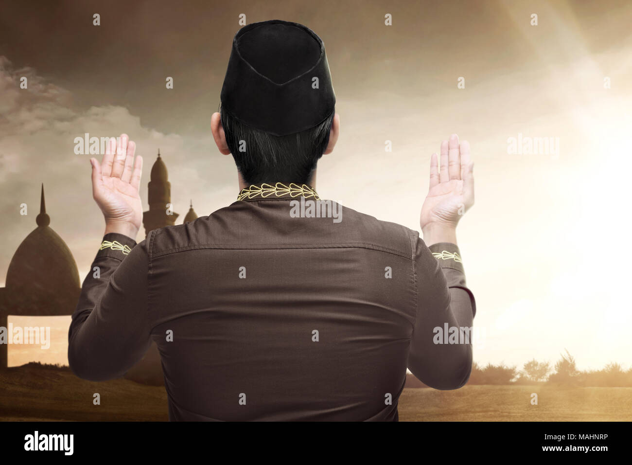 Back view of asian muslim man with cap praying to god with sunlight ...