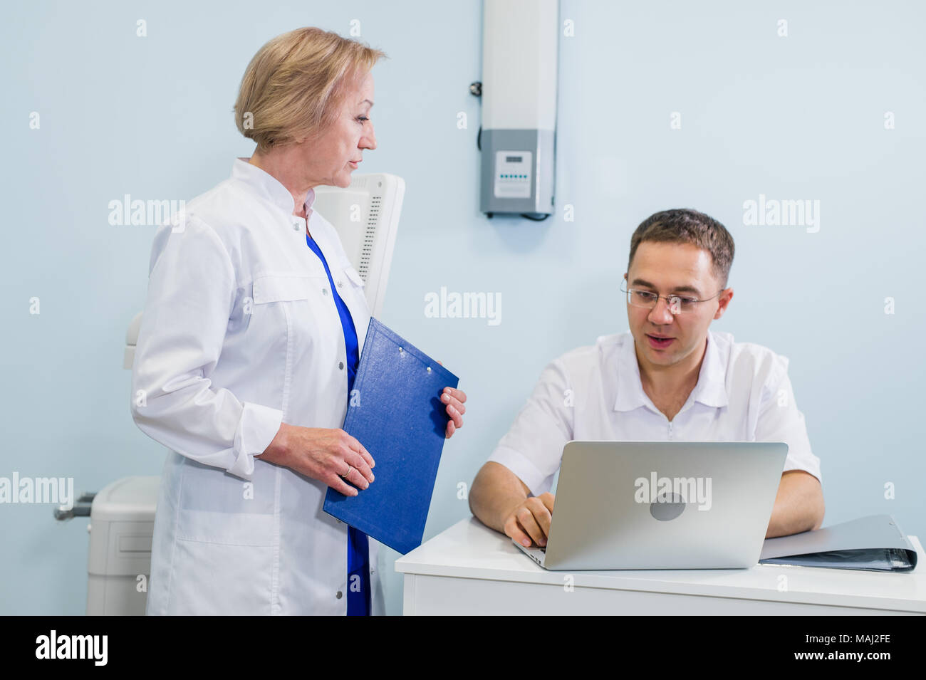 Doctor and nurse reviewing patient information on a laptop computer in ...