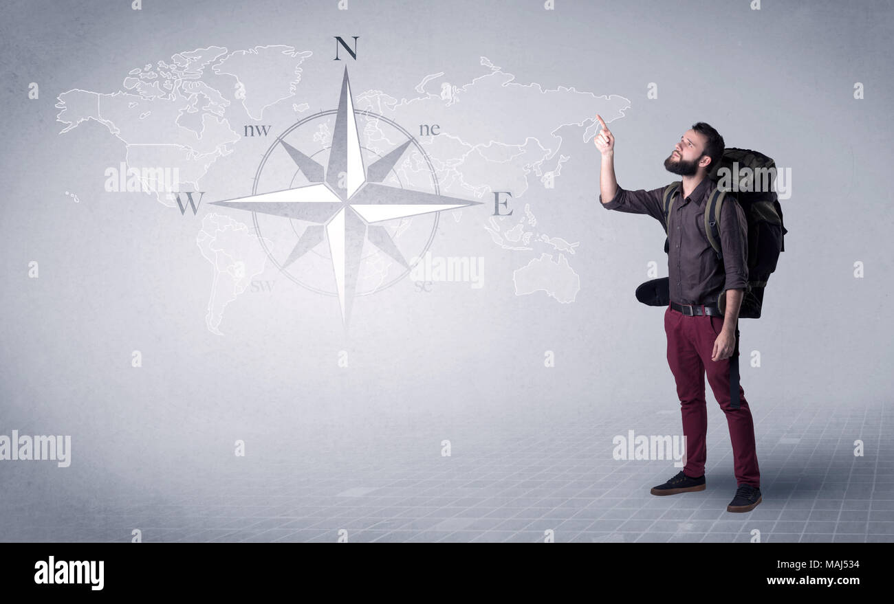 Handsome young man standing with a backpack on his back and a compass ...