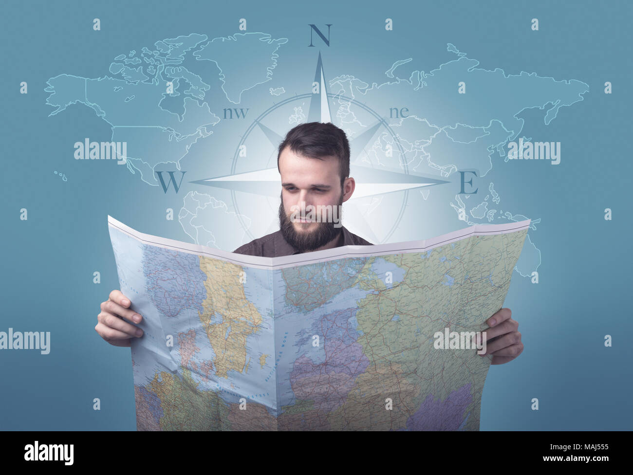 Handsome young man holding a map with a world map and a compass behind ...