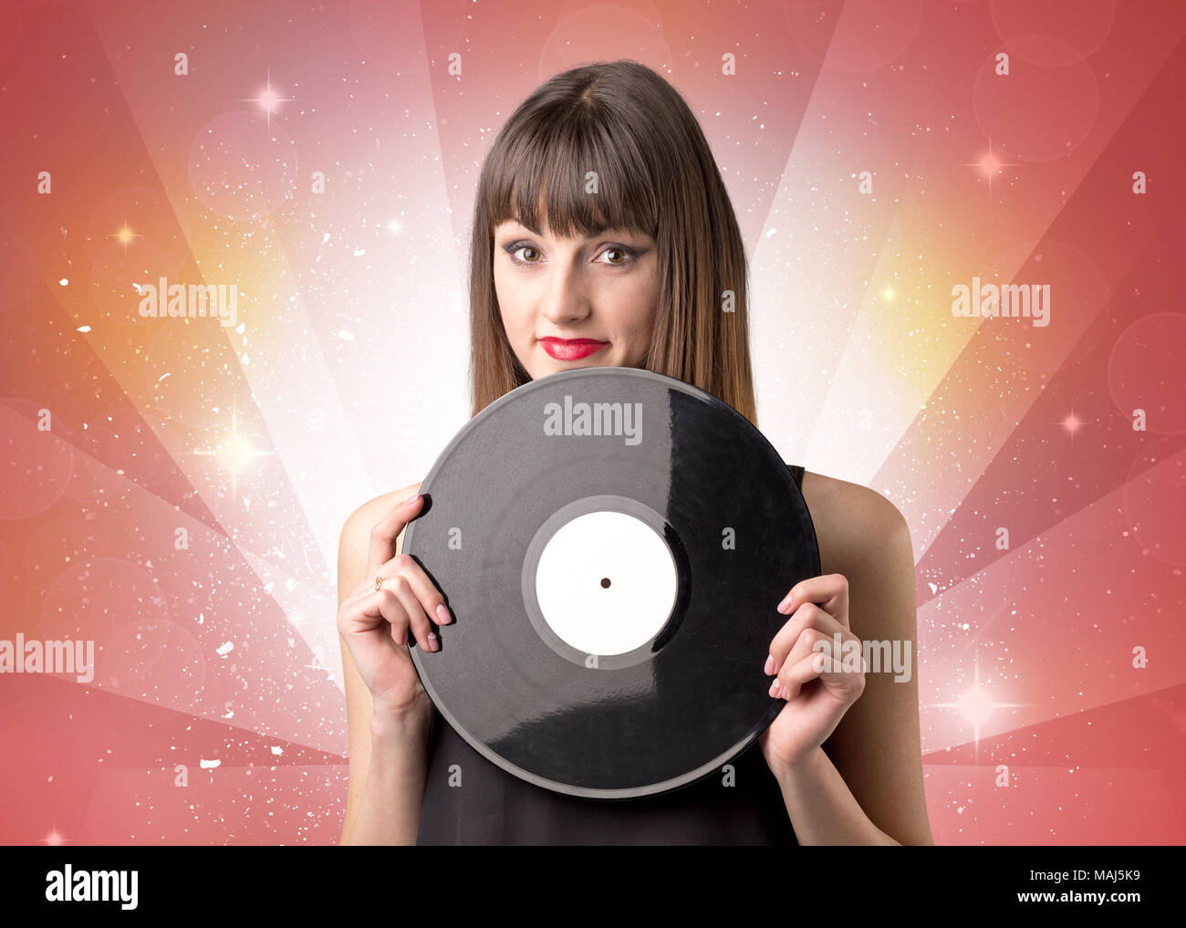 Young lady holding vinyl record on a red background with lights shining ...