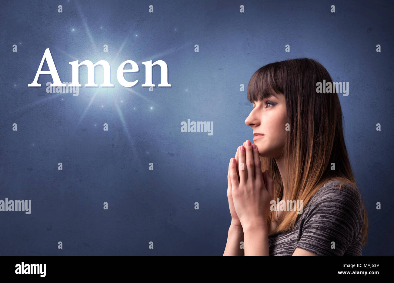 Young woman praying on a blue background with the word Amen written ...