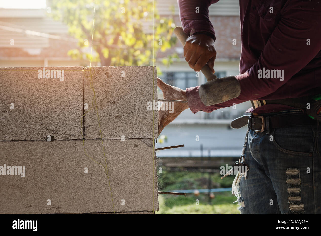 Mason worker building exterior walls, he using rubber hammer for laying ...