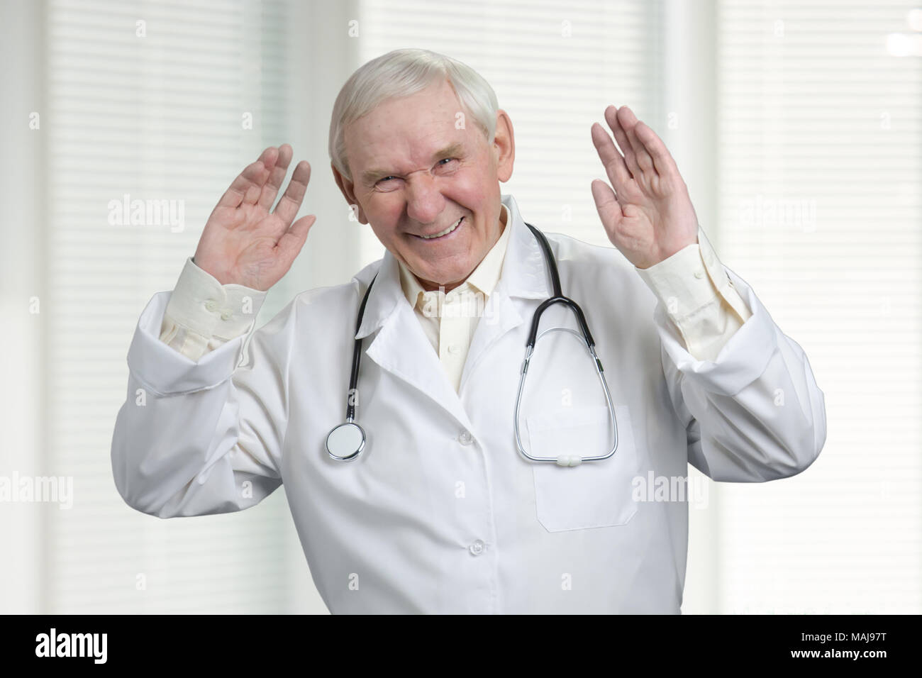 Senior doctor laughing hard with raised hands up. Doctor is kidding ...