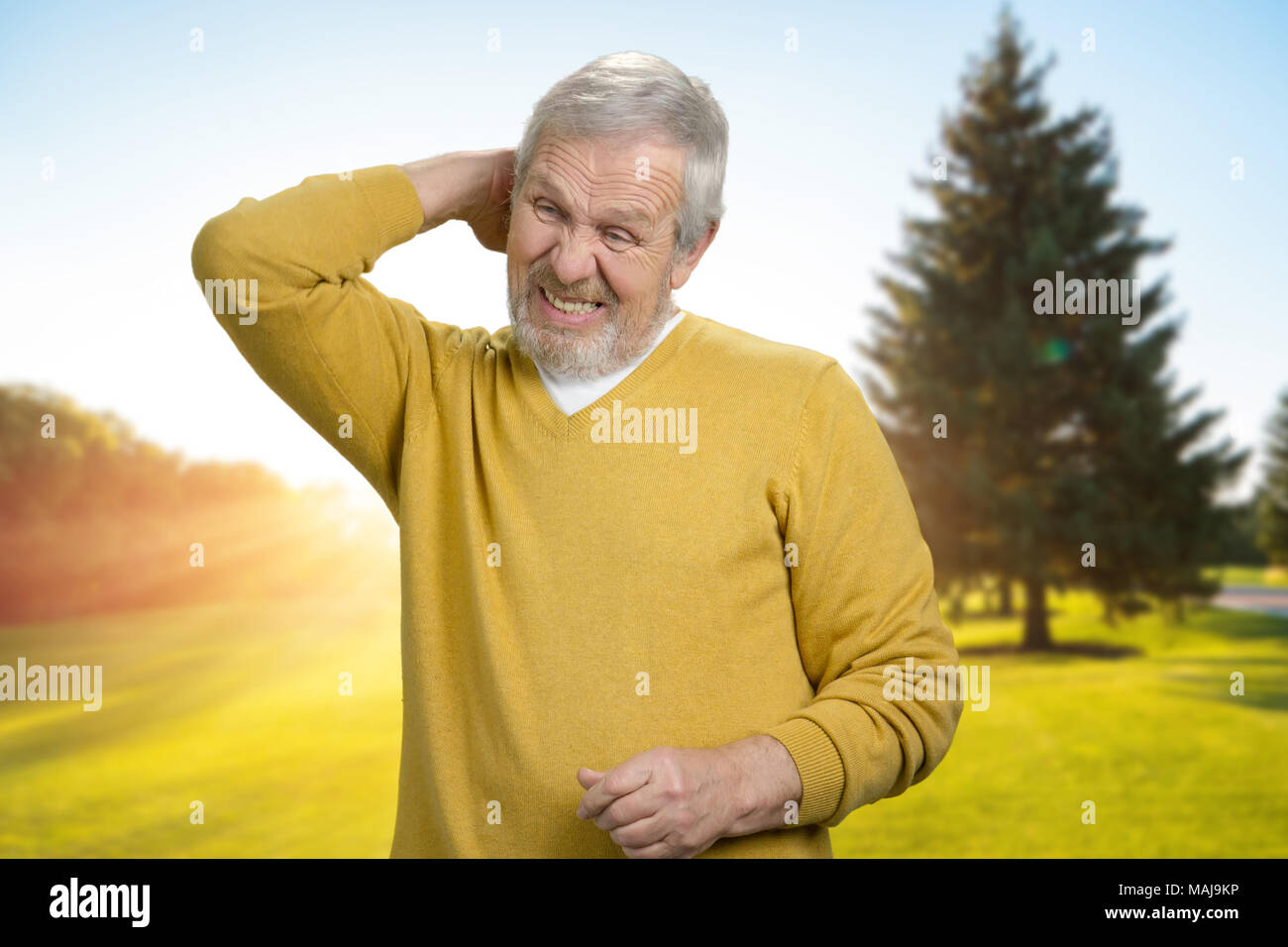 Handsome old man touching back of neck in pain. Suffering form neck ...