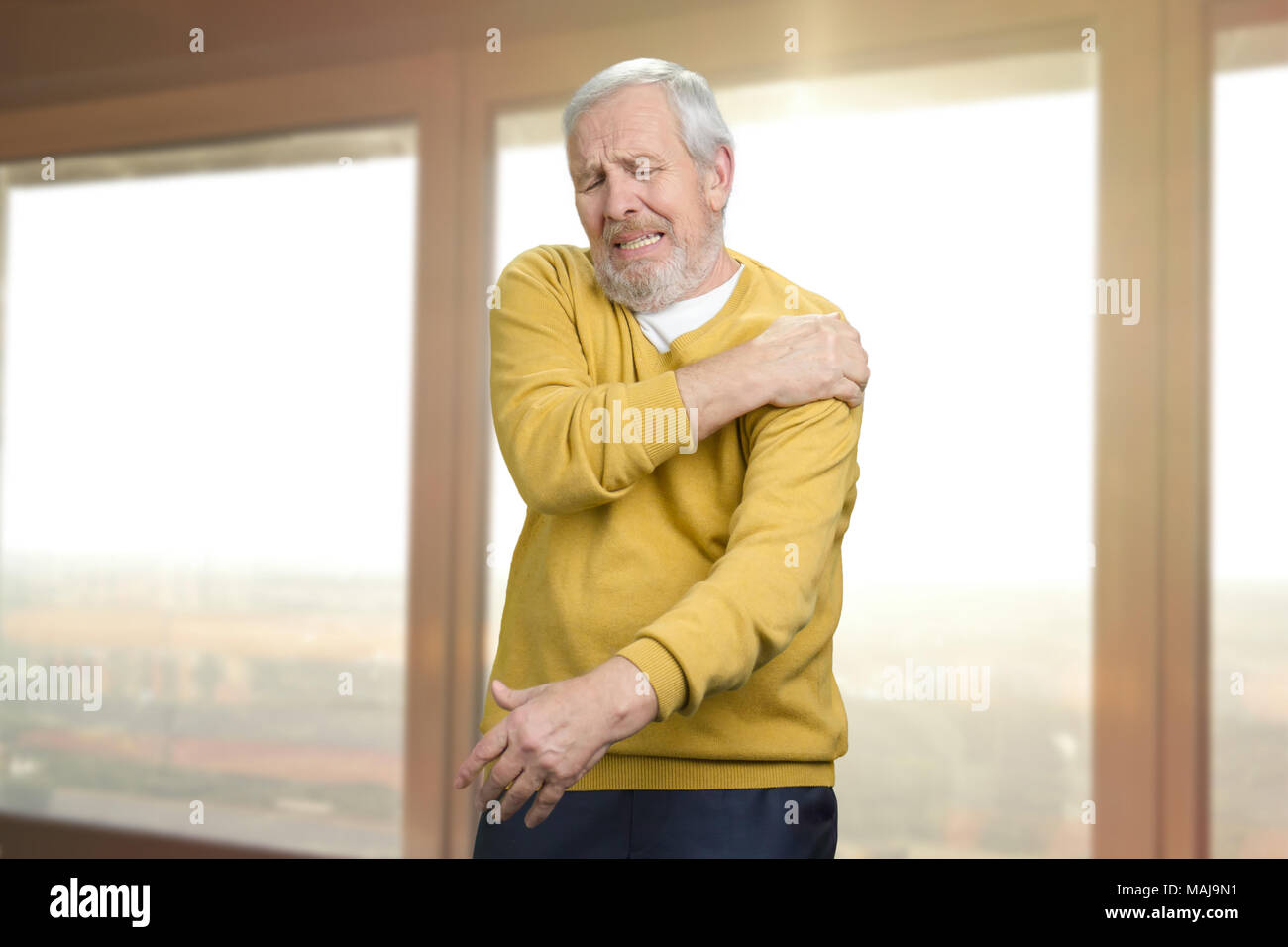 Old senior man with shoulder pain. Grandpa with shoulder inhury at home ...