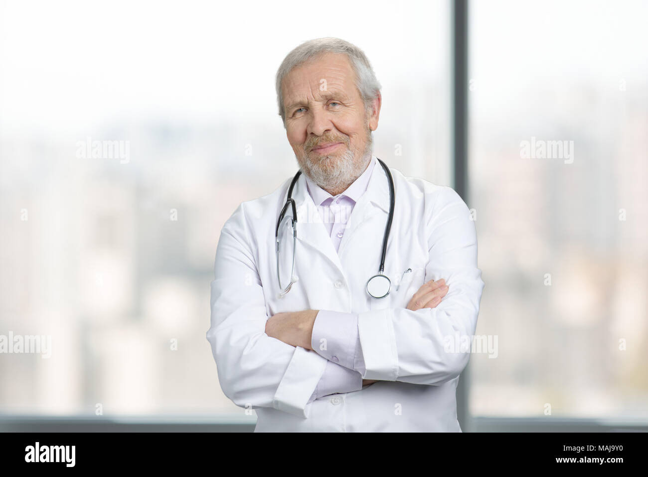 Kind, experienced old doctor. Portrait of senior physician with arms ...