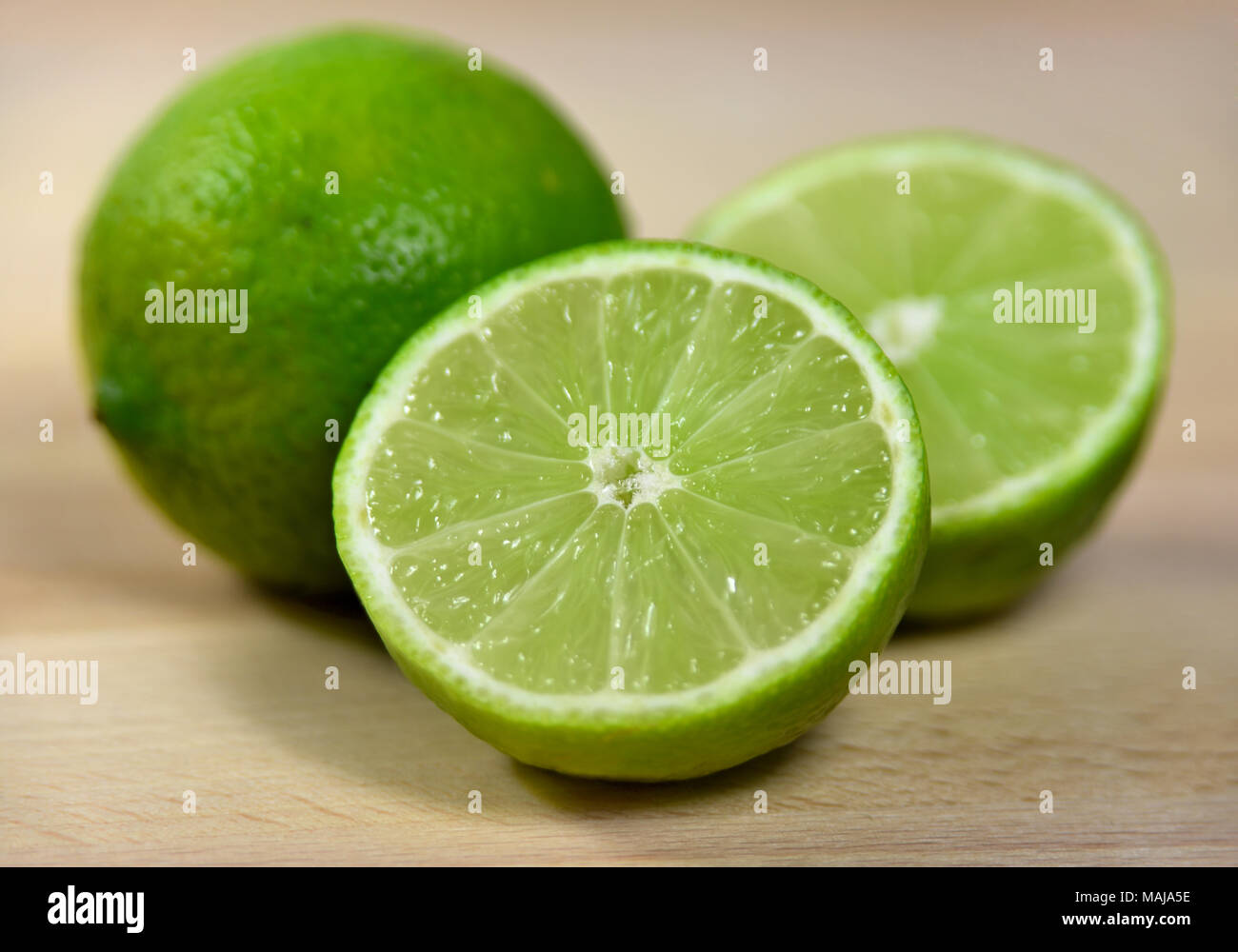 Fresh limes, isolated on wooden table. Cross section and whole lime ...