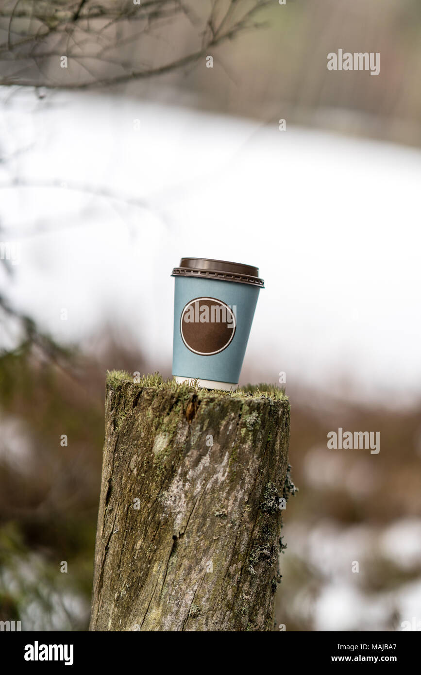 coffee cup on the old tree truunk in forest in winter. cold and ...