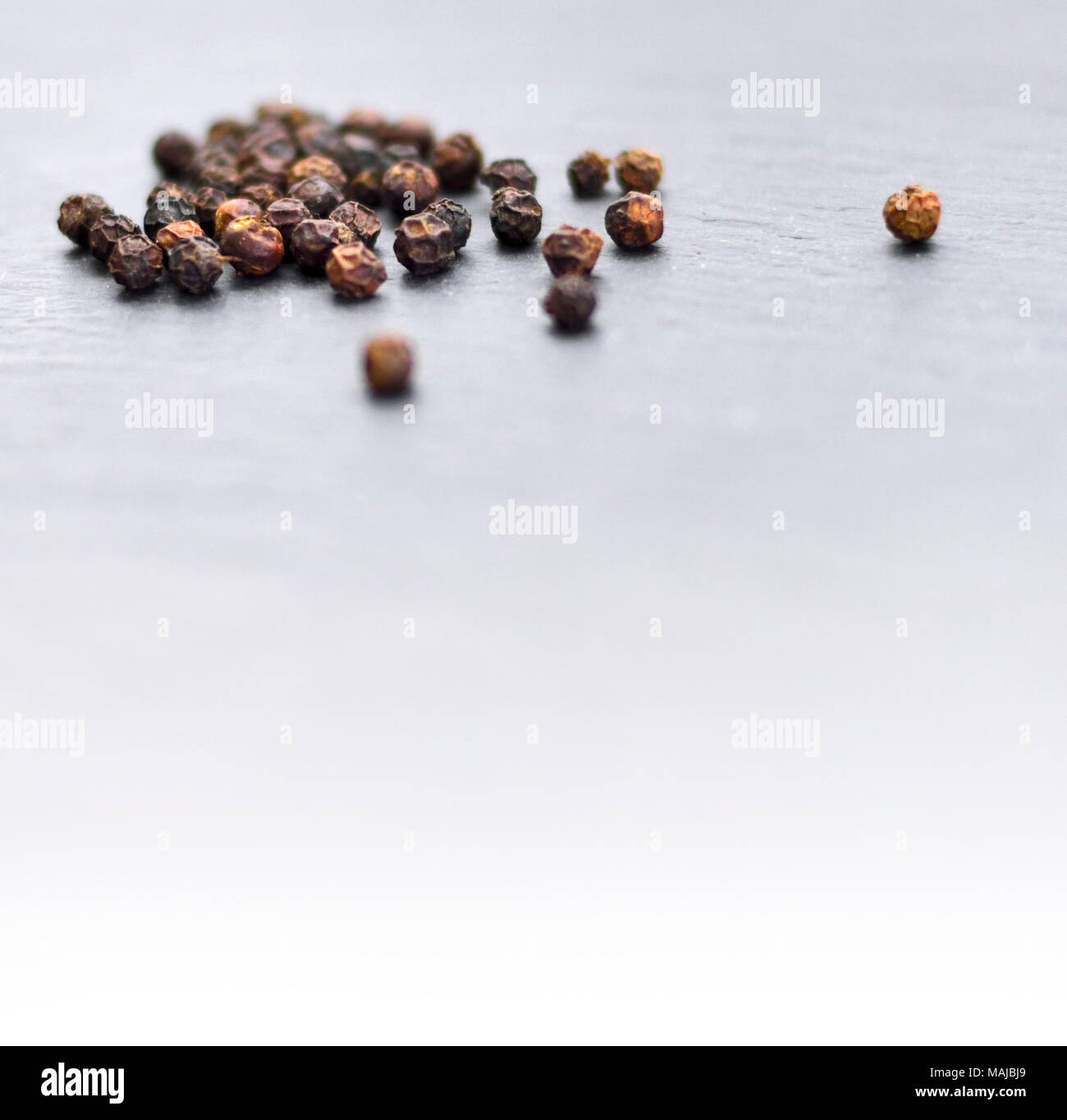Pile of black peppercorns on a slate plate. Food background with copy ...